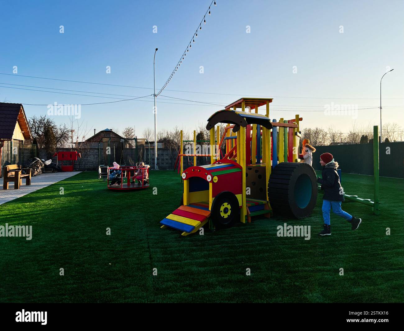 Kids playing on vibrant play structures in a backyard playground under ...