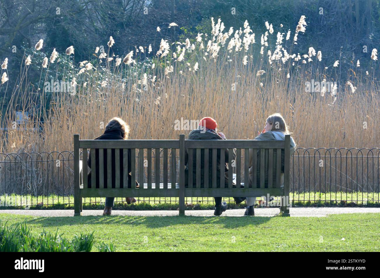 London, UK. Three Women sitting on a bench in St James's Park, February ...