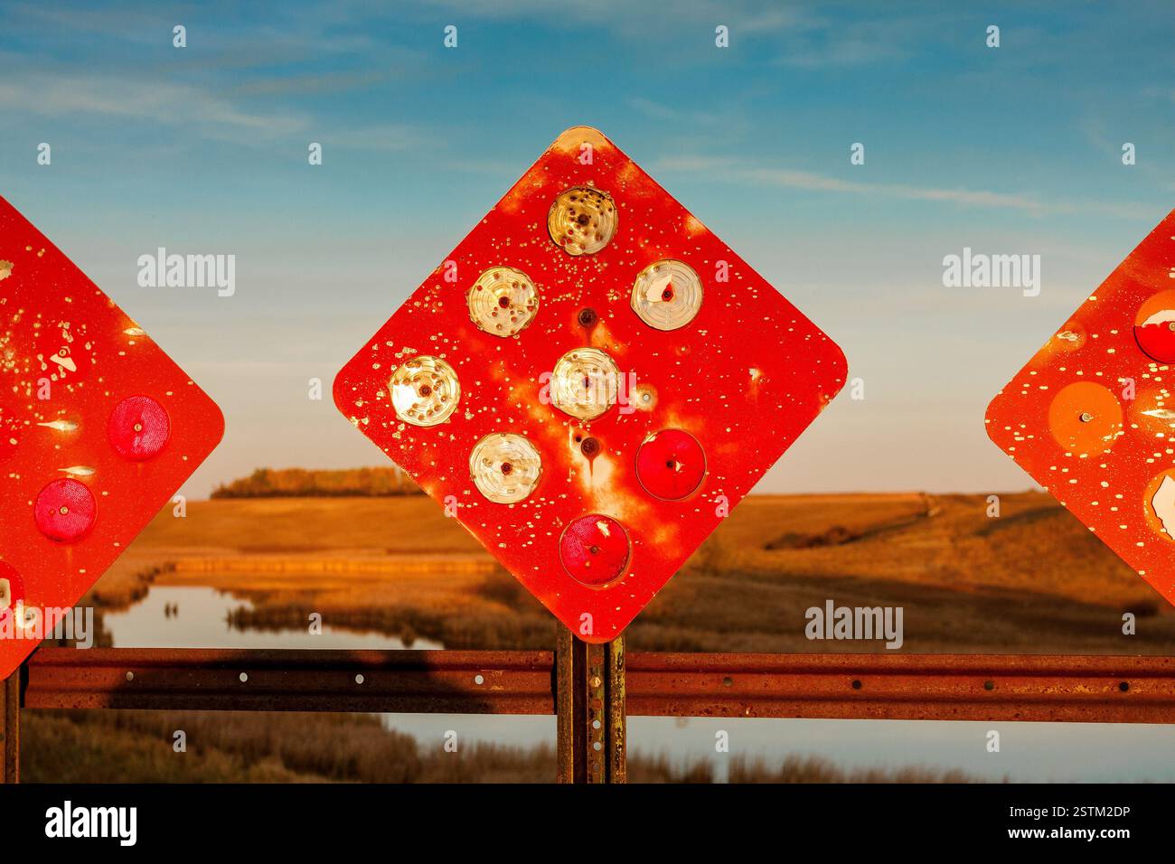 Three diamond-shaped orange and red road signs, adorned with reflectors ...