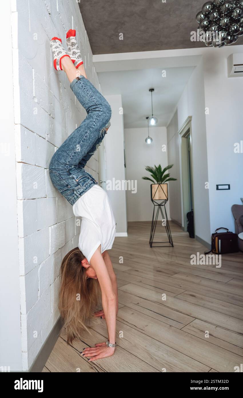 A woman is standing on his hands upside down in the living room Stock ...