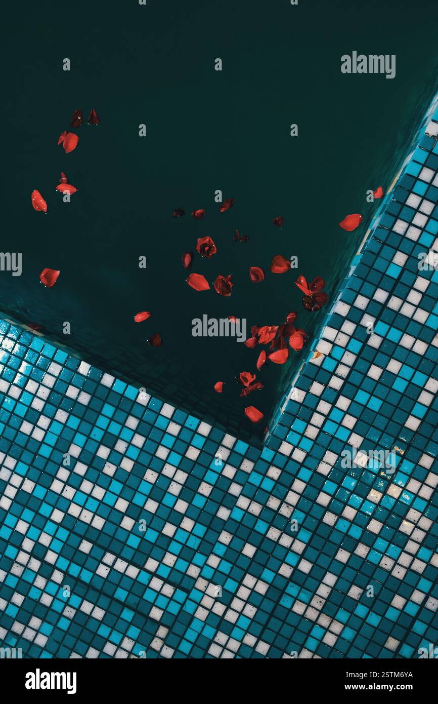 Spa bath with deep green water and some rose petals on surface ...