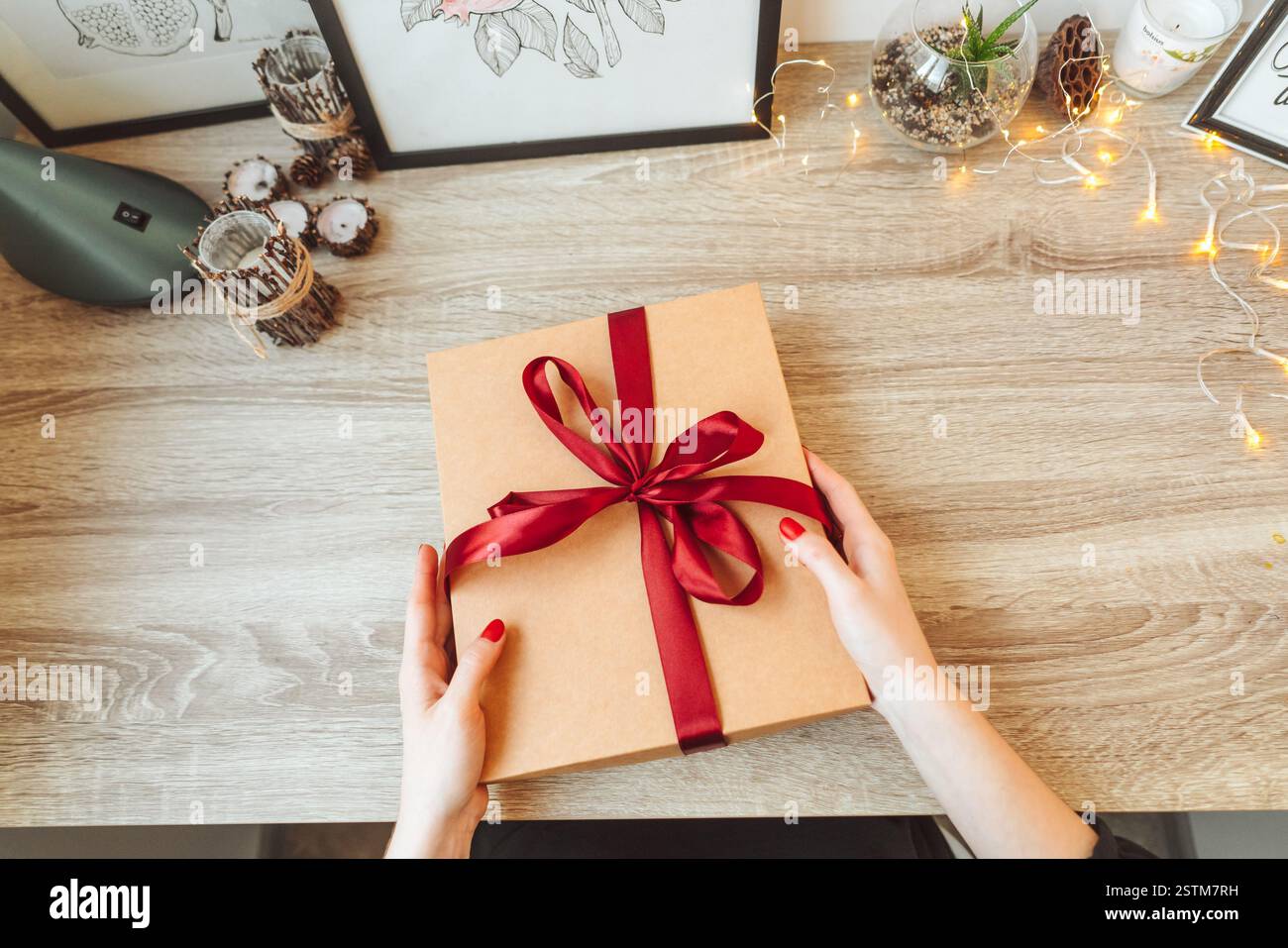 Woman wrapping present in paper with red ribbon Stock Photo - Alamy