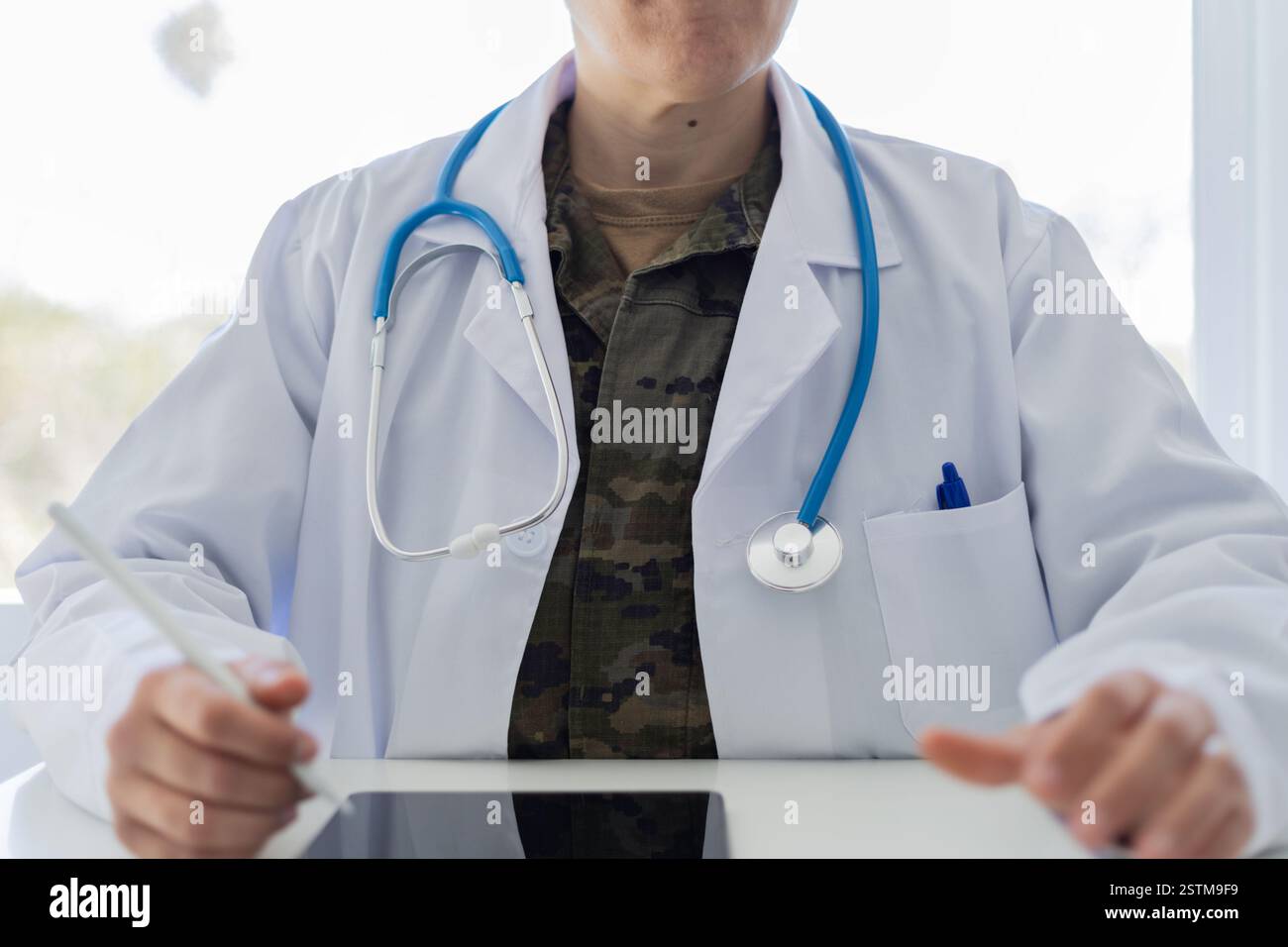 Military medic dressed in camouflage uniform under a white coat, with a ...