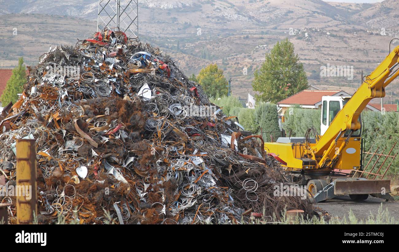 Pile of scrap metal and digger at recycling facility hi-res stock ...