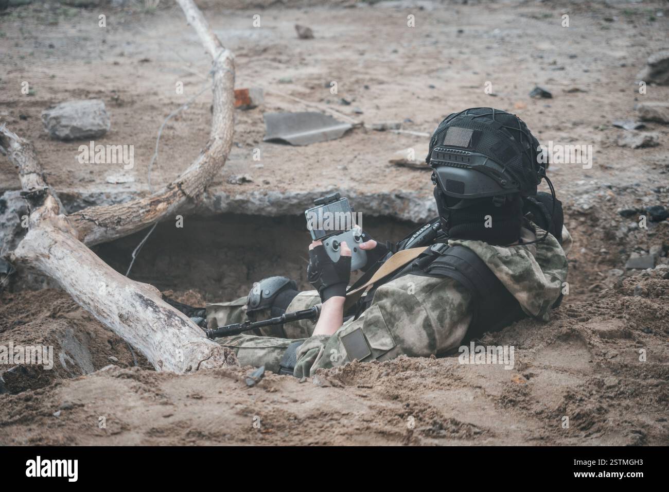 UAV operator with a remote control sitting in a trench. The concept of ...