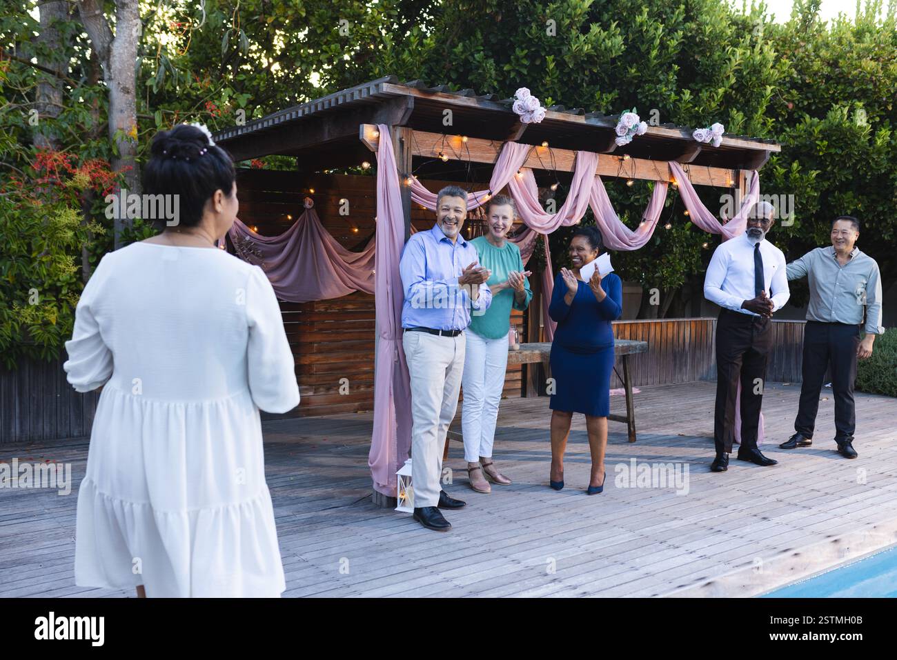Diverse senior friends clapping and celebrating by poolside under ...