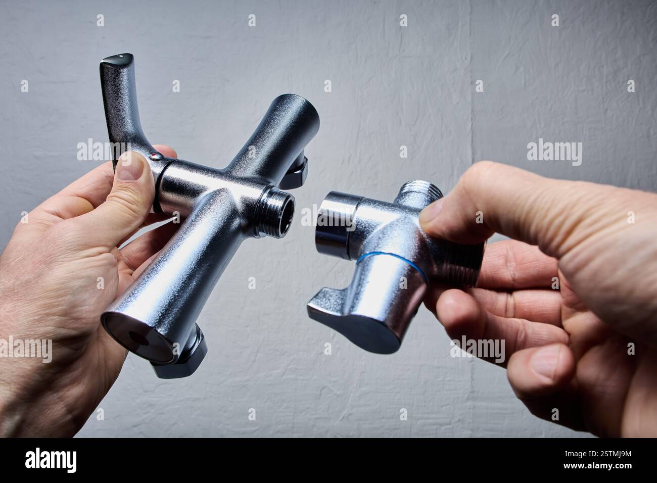 Two hands hold parts of disassembled mixer tap, including main body and ...