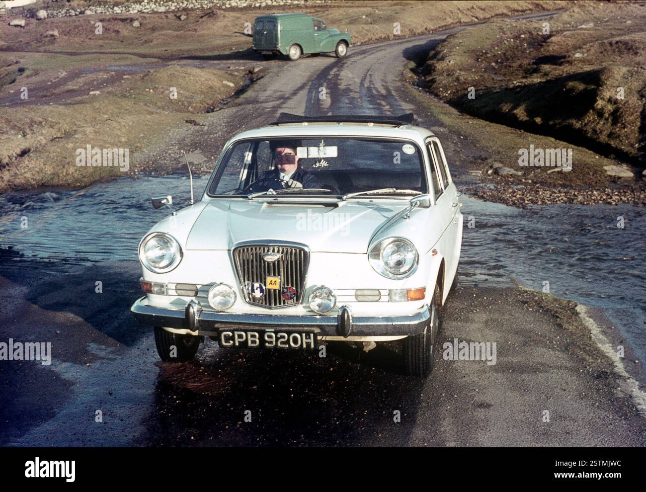Unidentified female driver in the 1970s driving through a small river ...