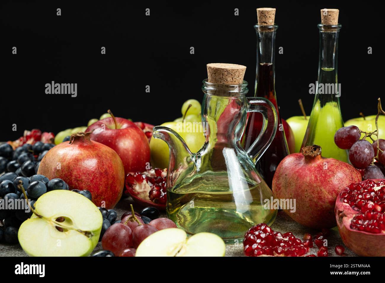Vinegars in glass vinegar bowls on black background among fruits Stock ...