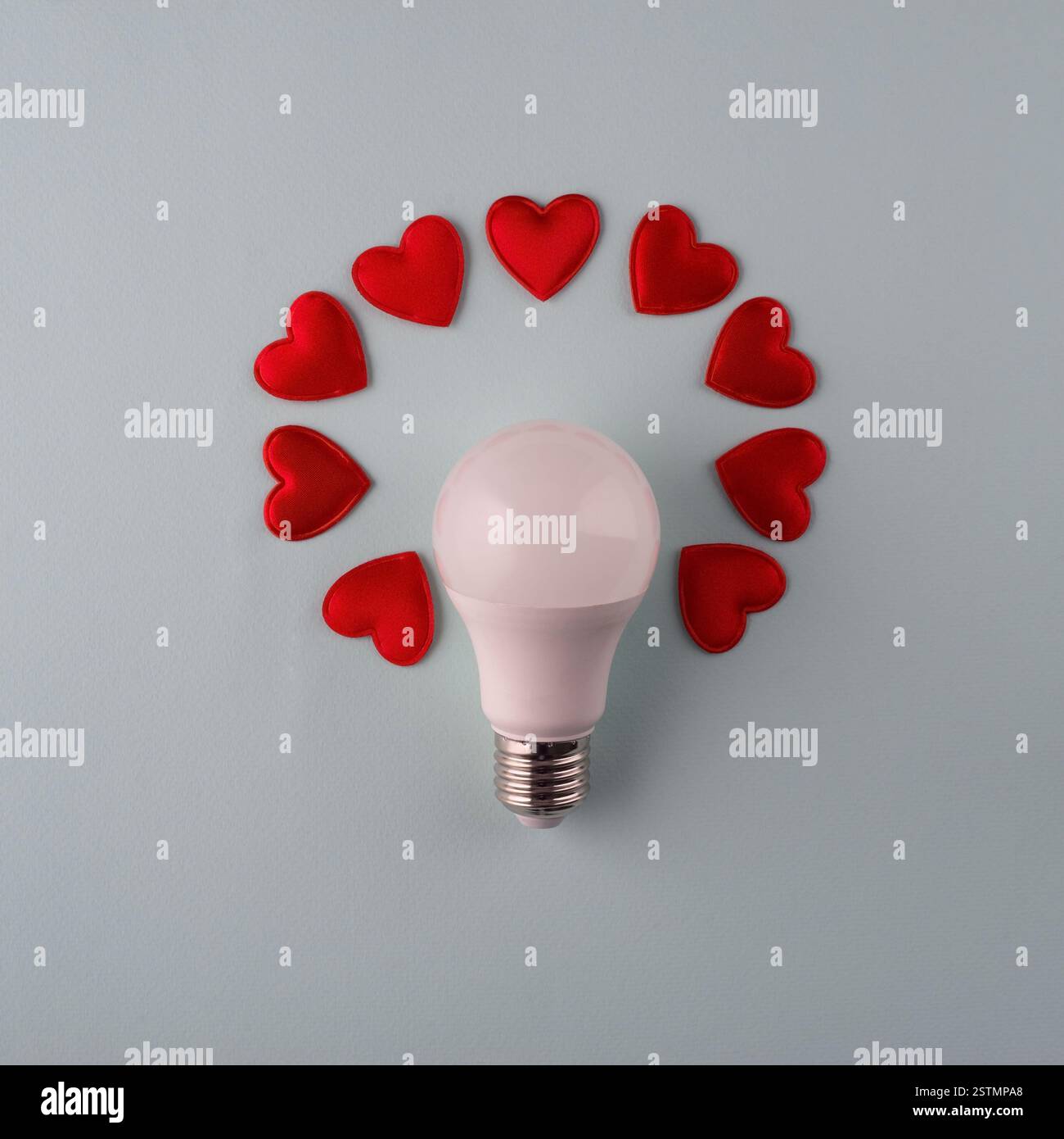light love concept from hearts around light bulb on blue background ...