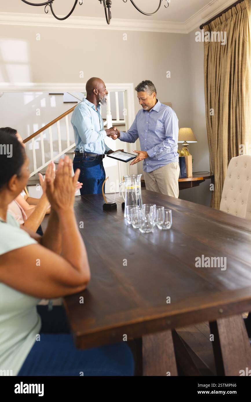 Senior men shaking hands at home, celebrating achievement with family ...