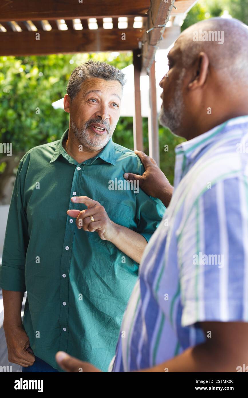 Two senior male diverse senior friends enjoying conversation outdoors ...