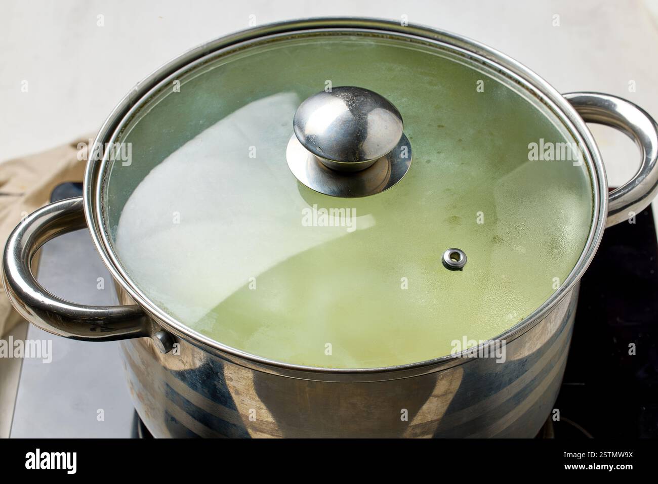 a pot with a closed, dewy lid on the stove. process of making dinner ...