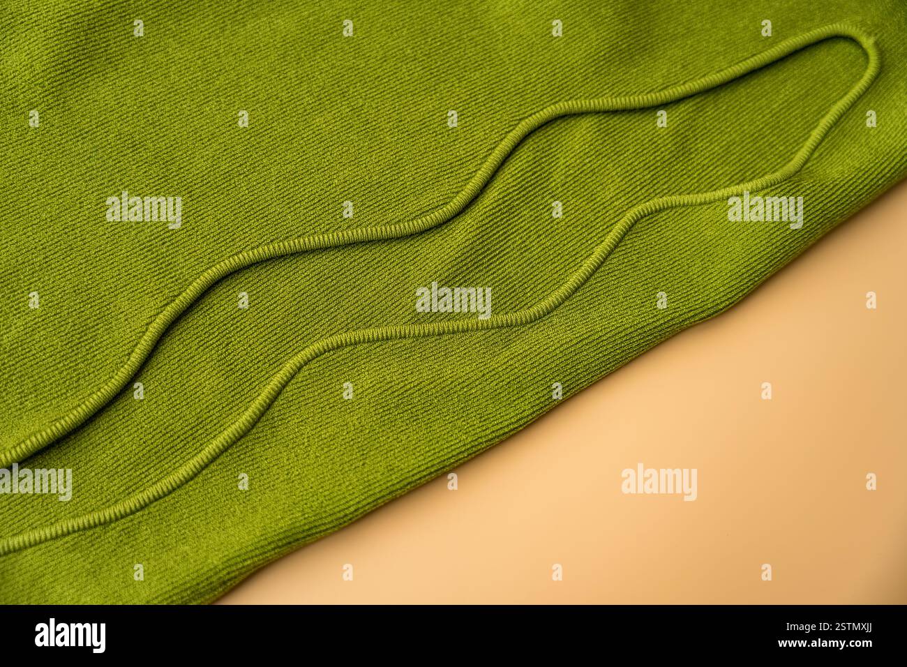 Moss green ribbed fabric with wavy stitched details on beige background ...