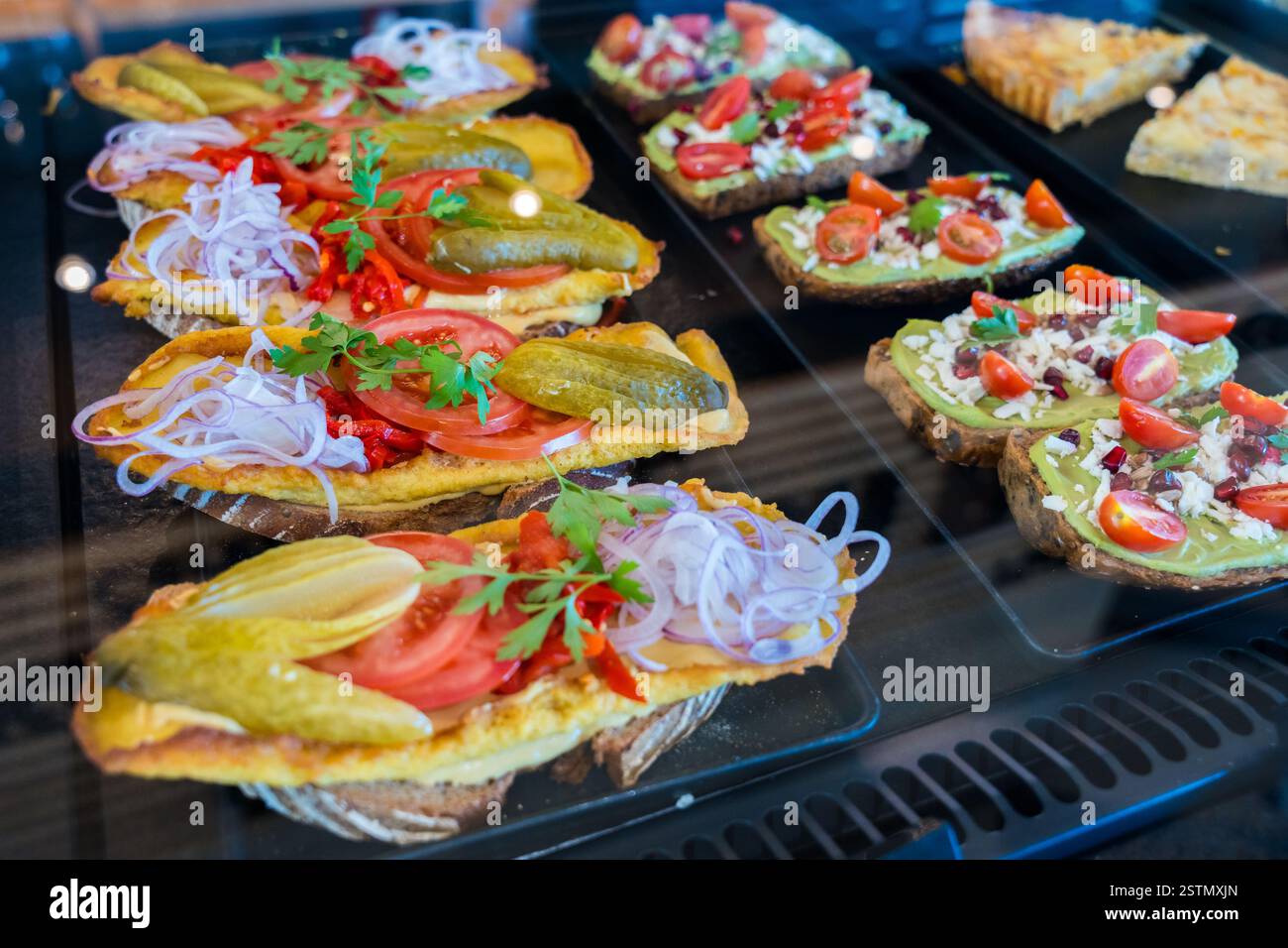 Assorted open-faced sandwiches with fresh toppings in a display case ...