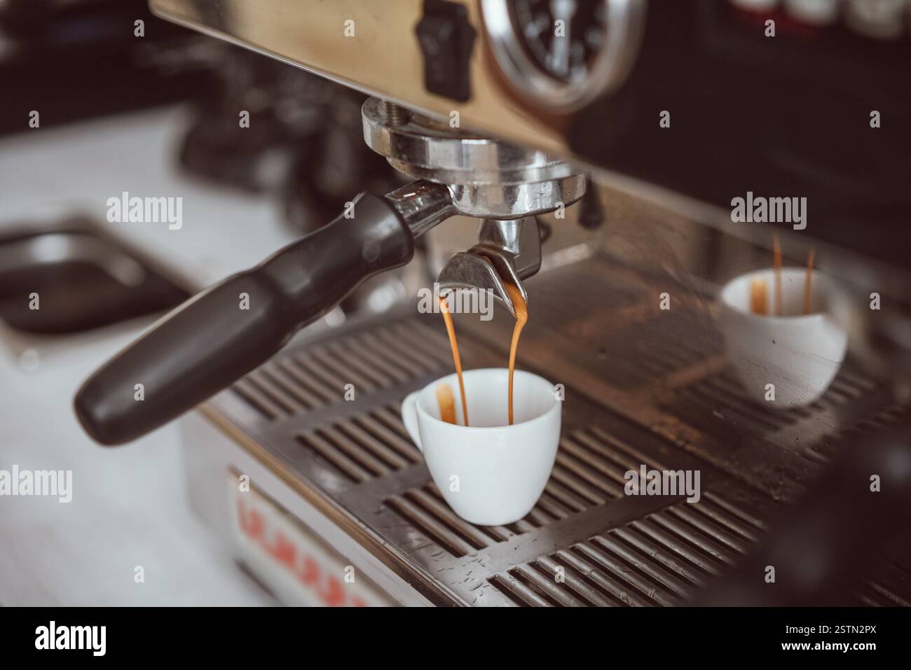 Professional espresso machine pouring fresh coffee into white ceramic ...