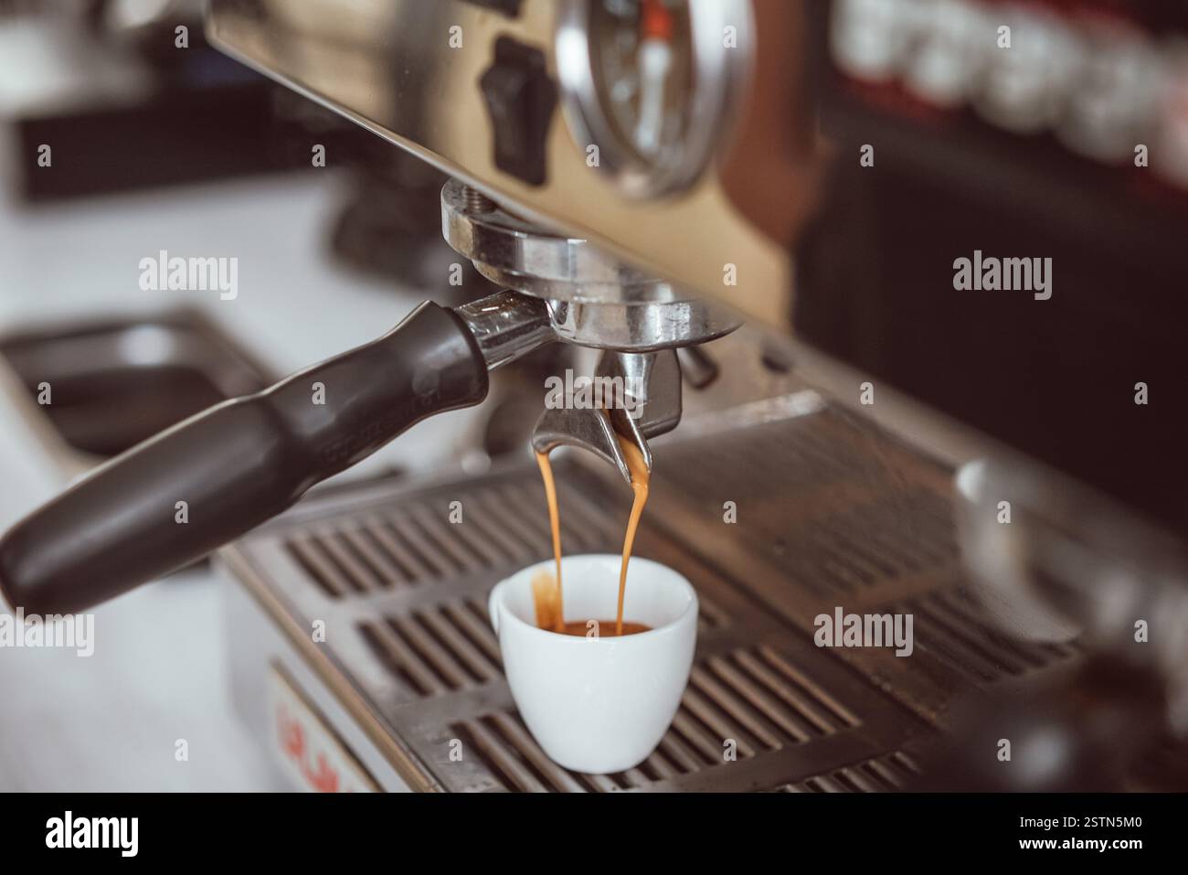 Professional espresso machine pouring fresh coffee into white ceramic ...