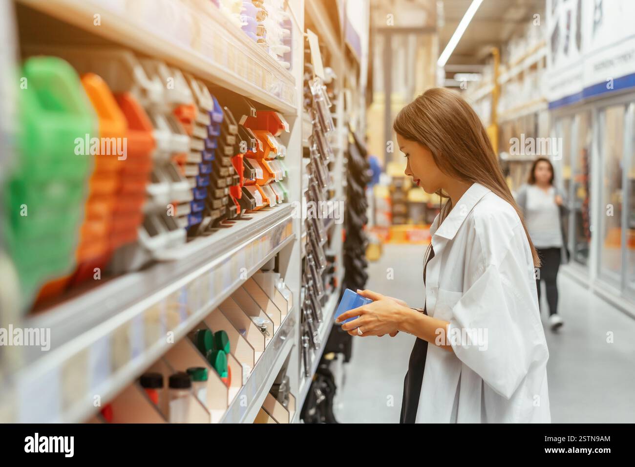 Woman chooses plastic boxes of different colors for the workshop, shop ...