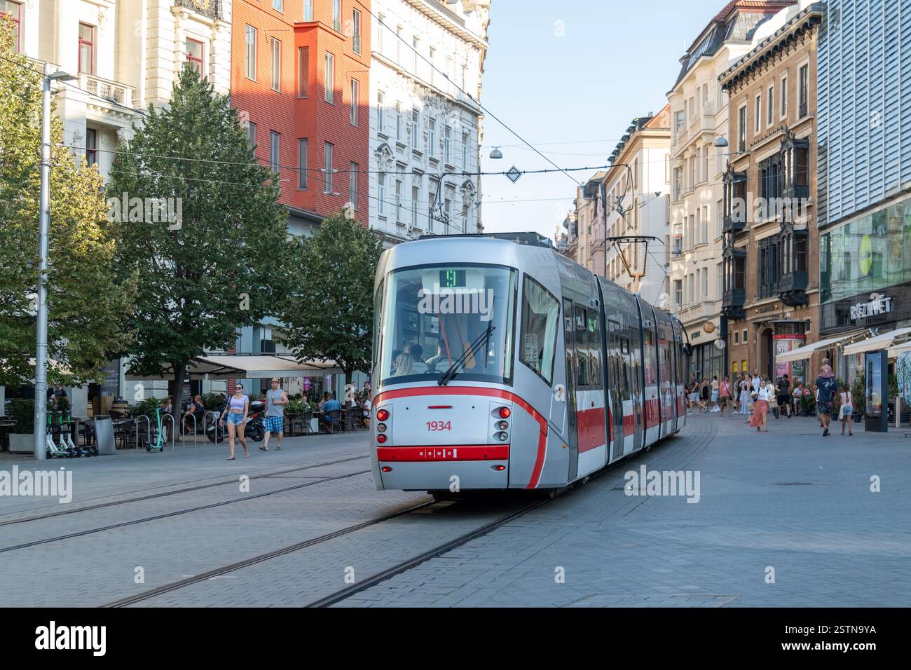 A modern tram travels through the bustling streets of Brno in the Czech Republic, surrounded by ...