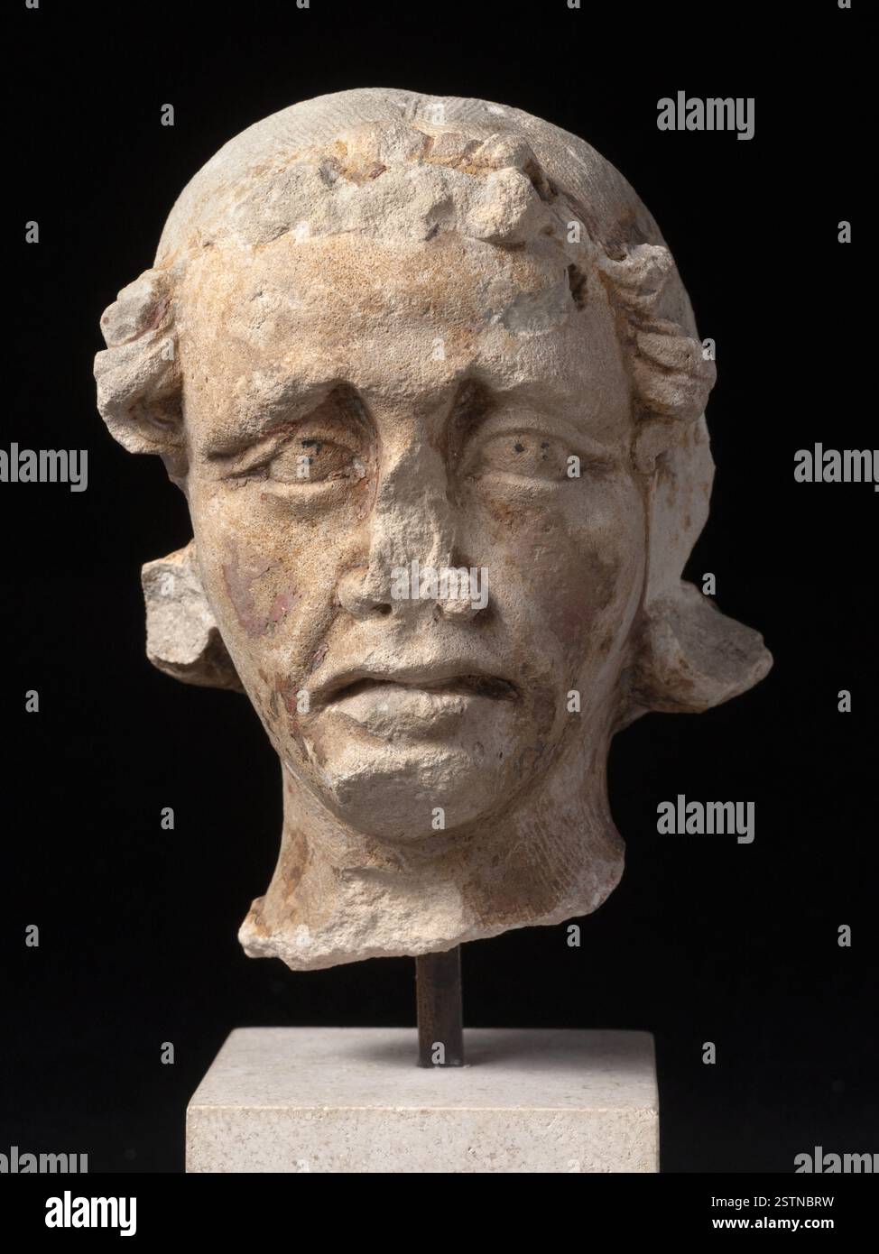 A carved bust of a man with curly hair and a cap, showing mutilations ...