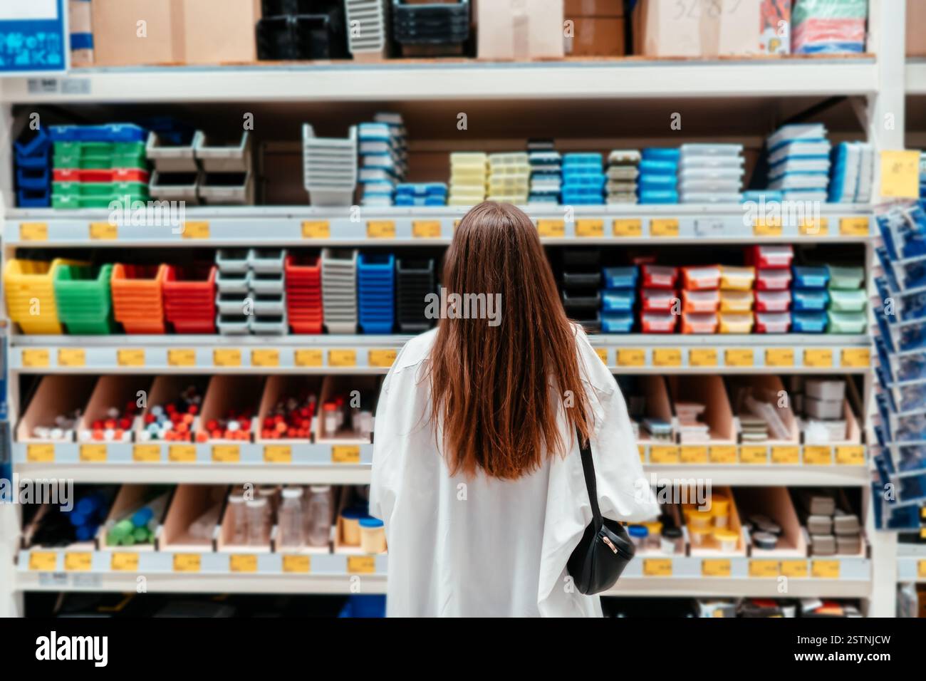 Woman chooses plastic boxes of different colors for the workshop, shop ...