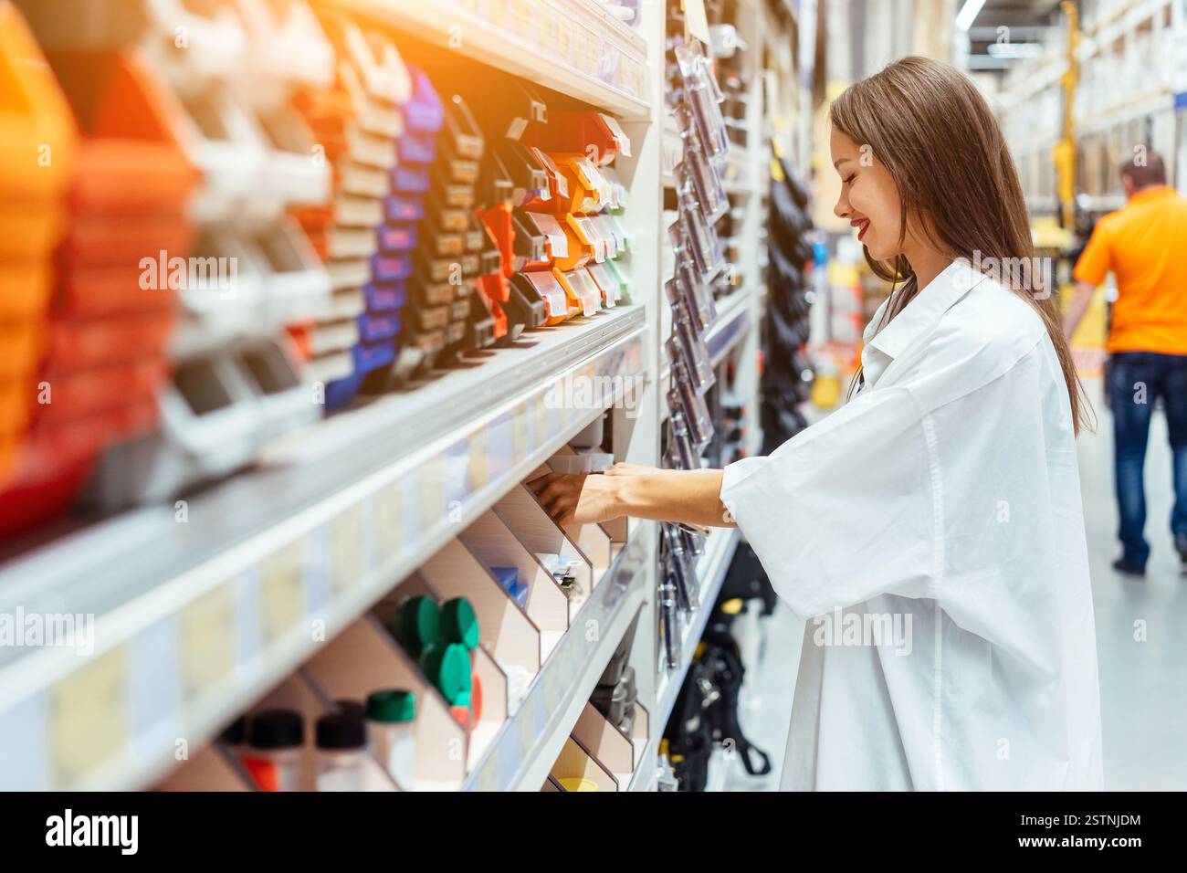 Woman chooses plastic boxes of different colors for the workshop, shop ...