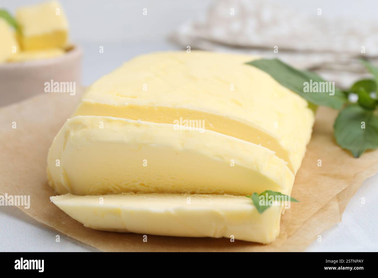 Cut brick of butter and basil on white table, closeup Stock Photo - Alamy
