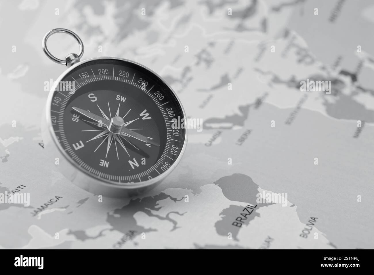 Compass on world map, toned in black-and-white Stock Photo - Alamy