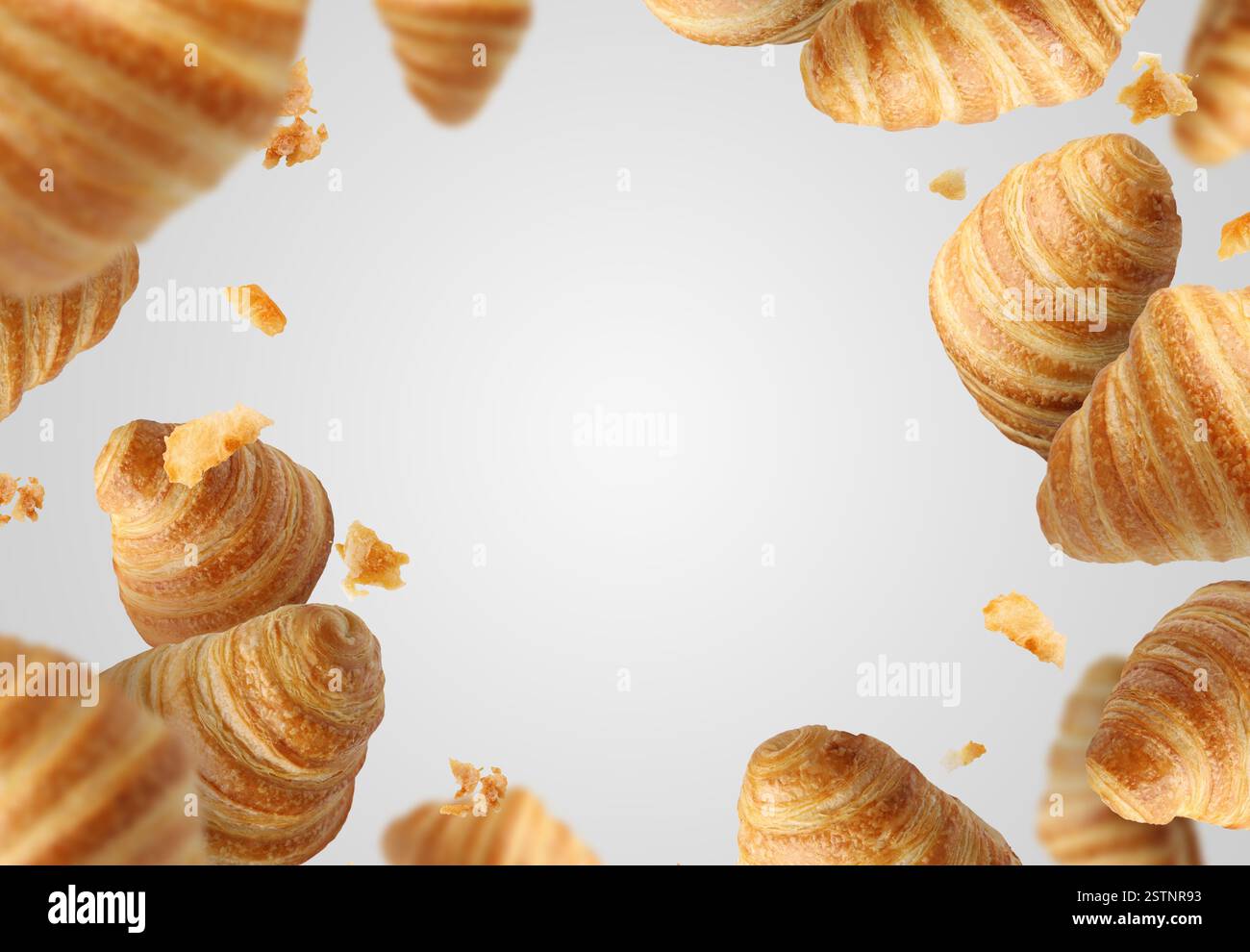 Delicious croissants and crumbs in air on grey background. Puff pastry ...