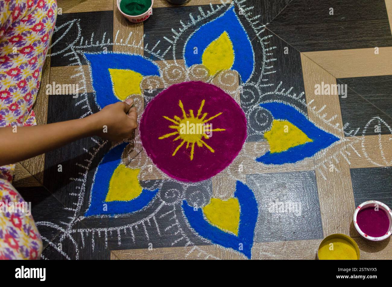 A Hindu young female drawing a Rangoli in the front yard on the ...