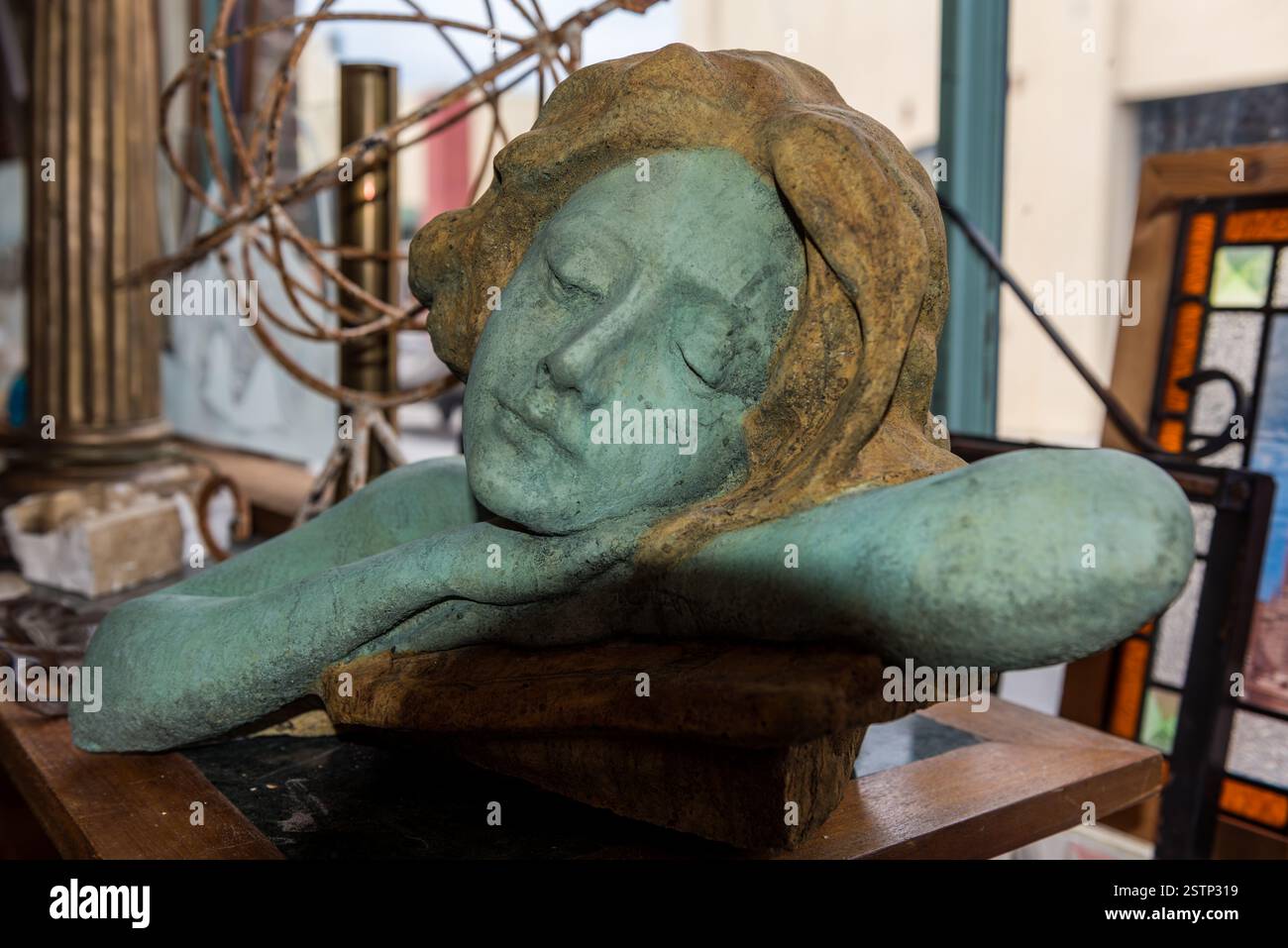 Sculpture of a woman, eyes closed, resting her head on her hands atop a ...