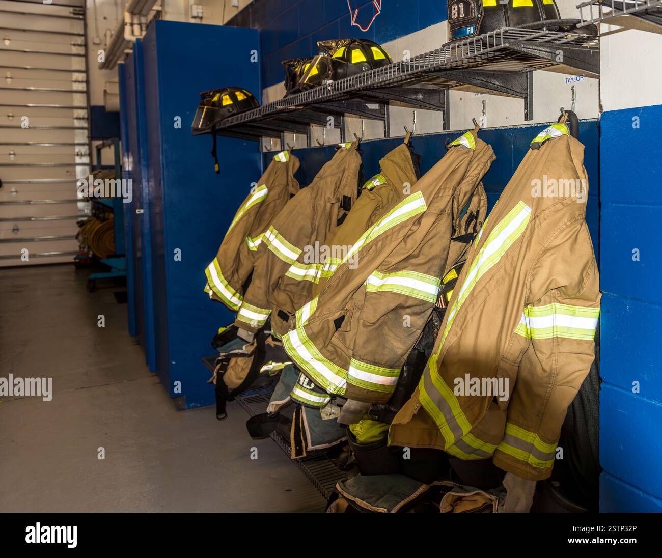 A row of firefighter coats hanging beneath a shelf with fire fighter ...