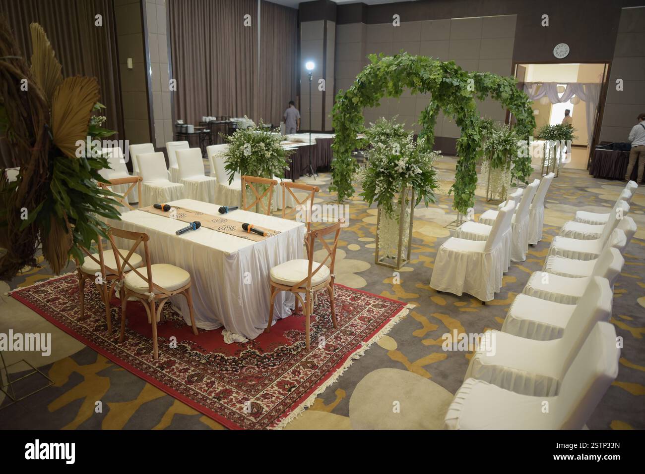 An elegant wedding ceremony setup showcasing a floral arch, beautifully decorated venue space ...