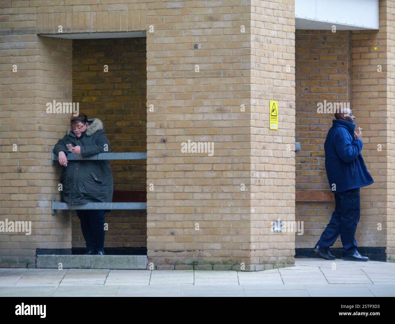 Braving the cold outdoors: Smokers congregate for a cigarette break on ...