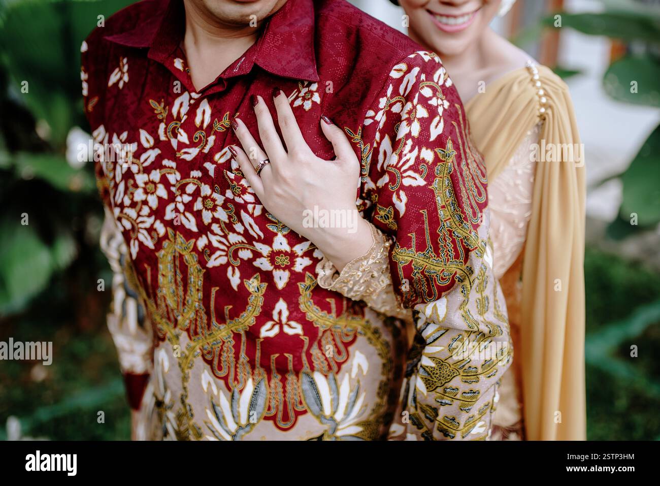 A newlywed couple shares an intimate moment, embracing while adorned in ...