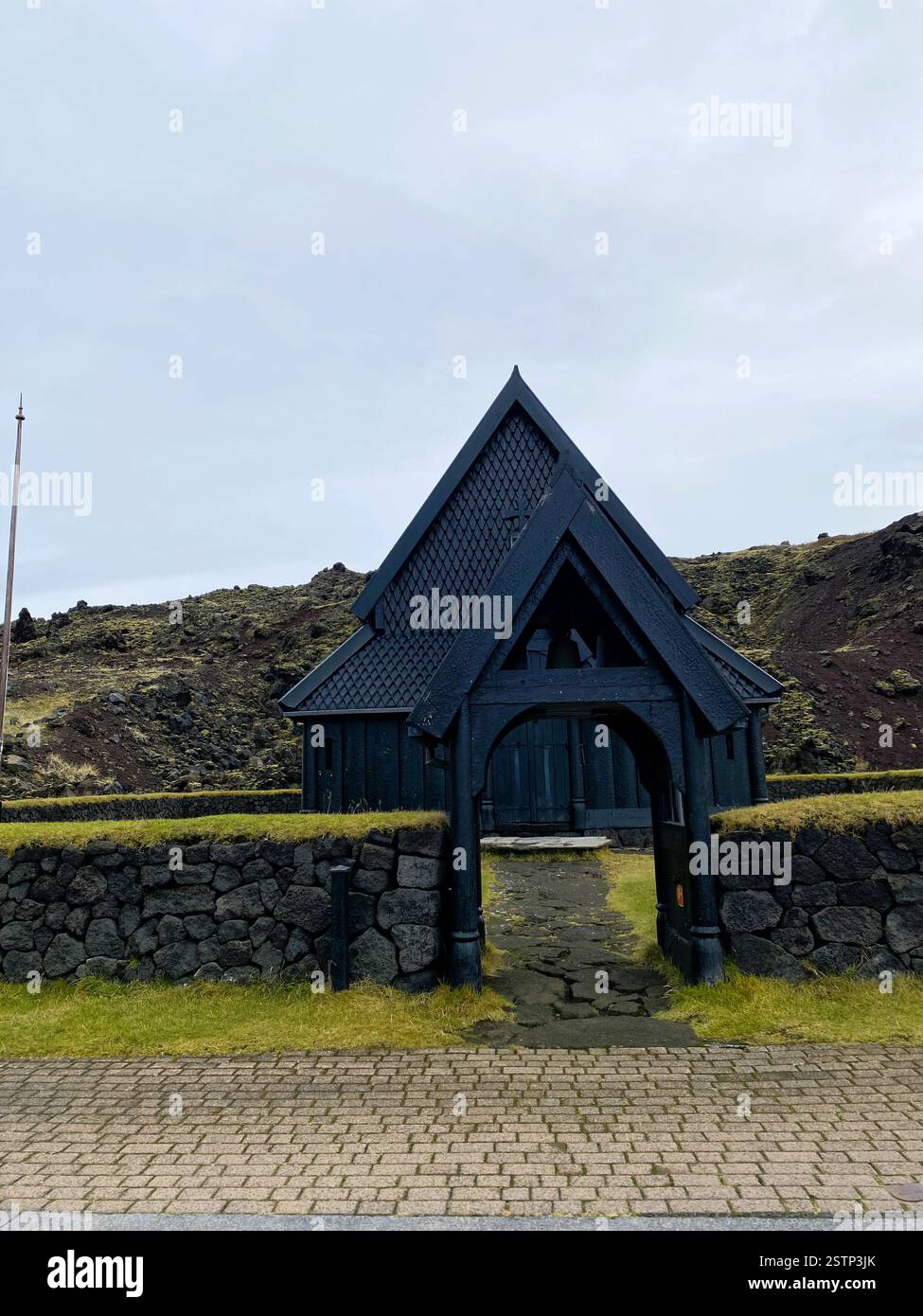 The image depicts a striking black wooden structure resembling a ...