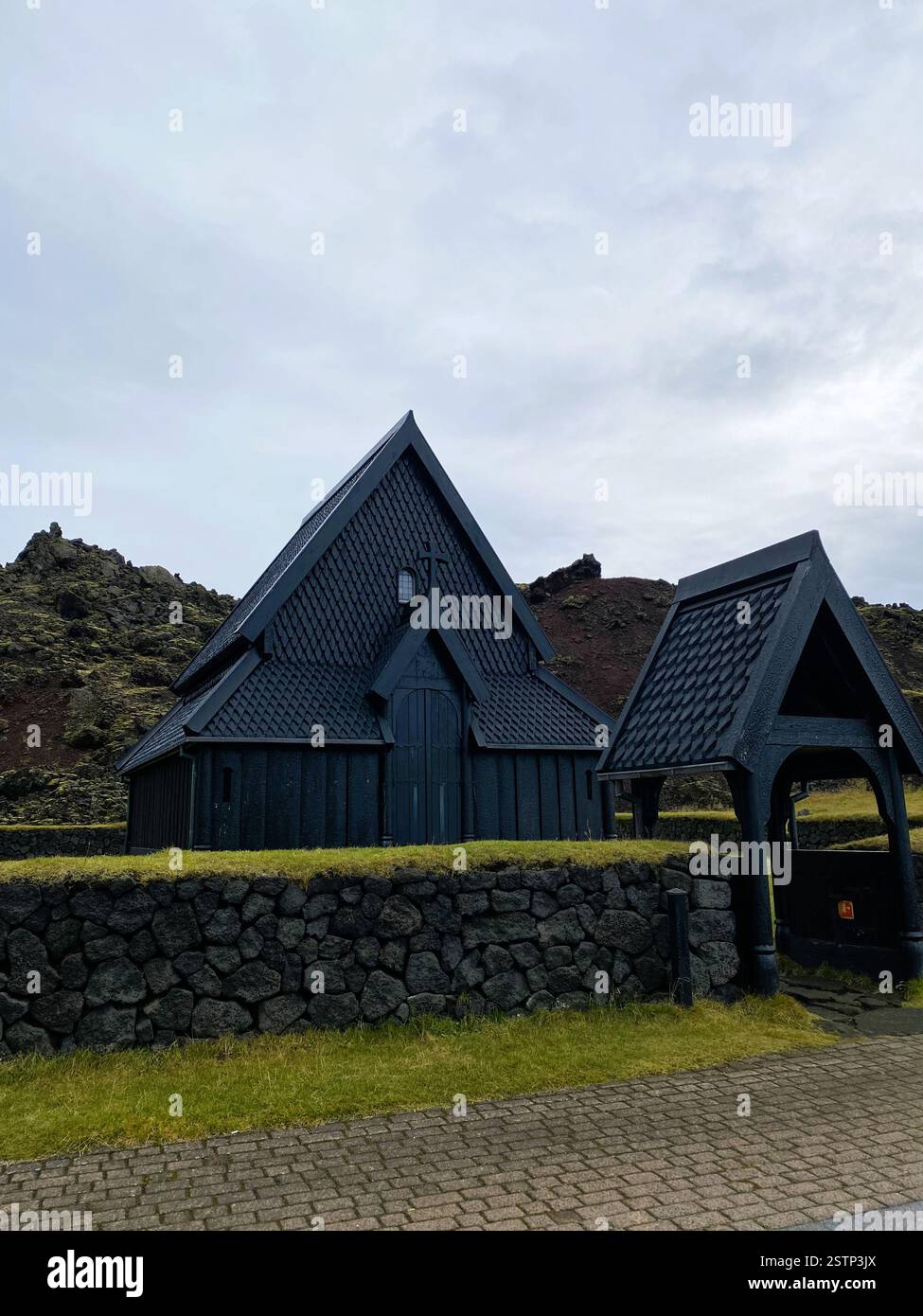 The image depicts a striking black wooden building resembling a ...