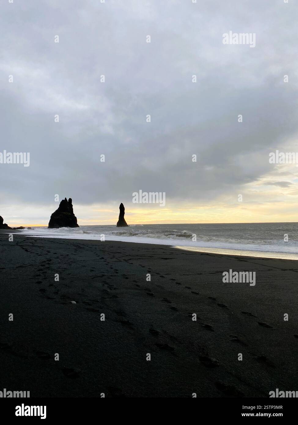 The image depicts a serene coastal scene with a black sand beach ...