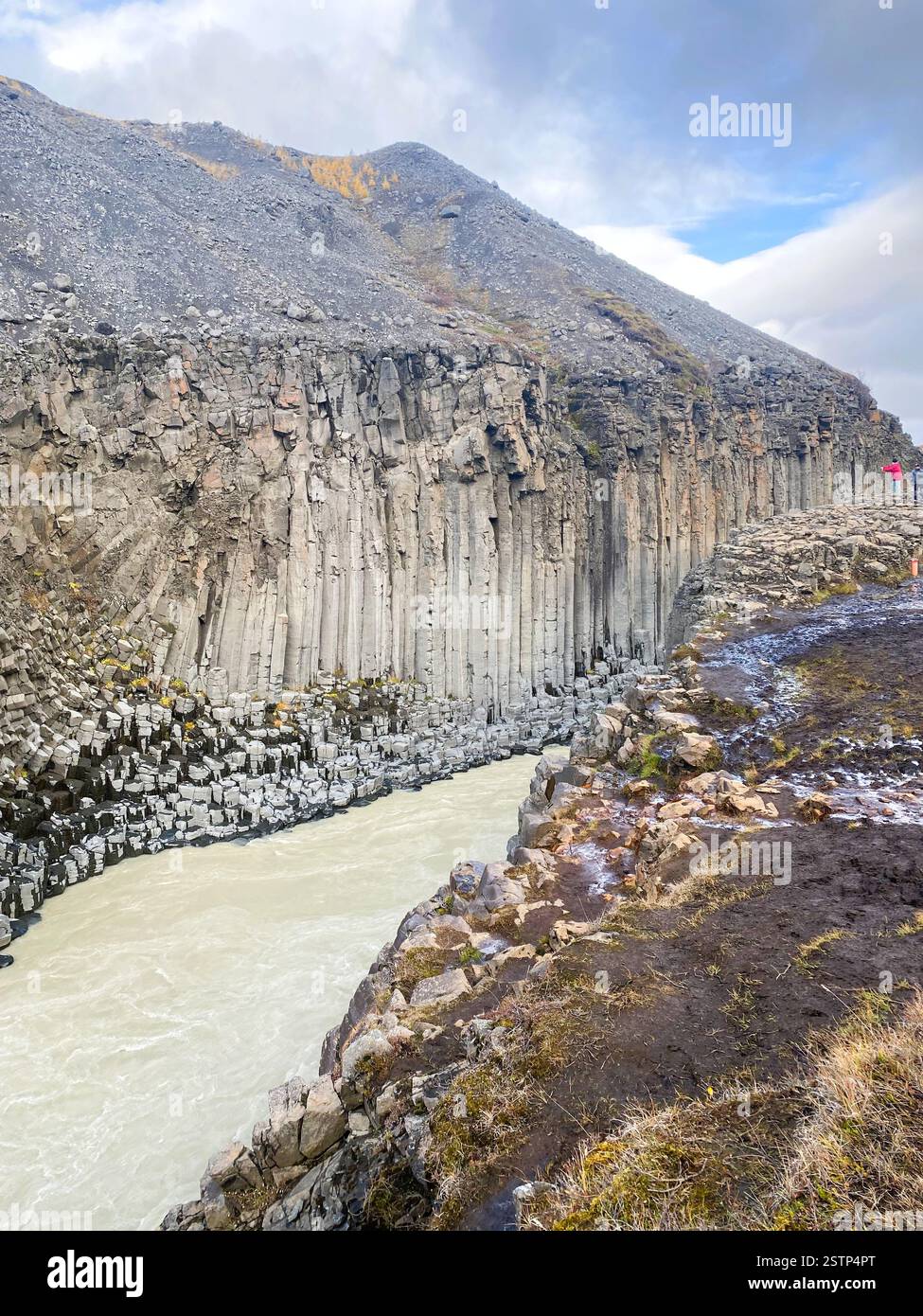 A dramatic landscape featuring a wide river flowing gently, flanked by ...