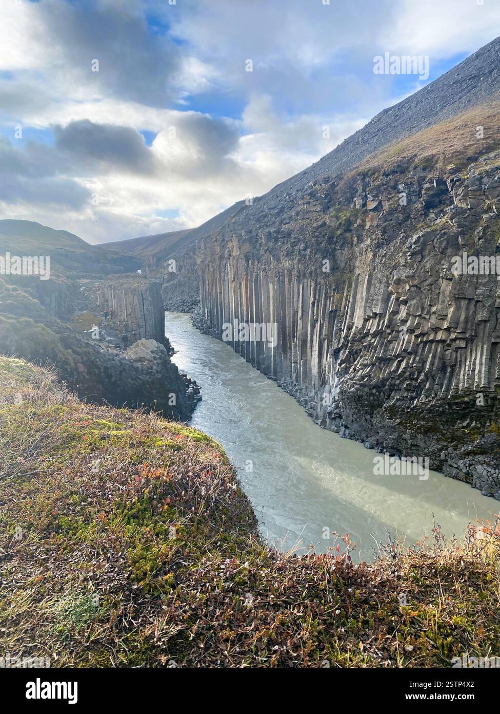 A dramatic canyon landscape featuring a river flowing between towering ...