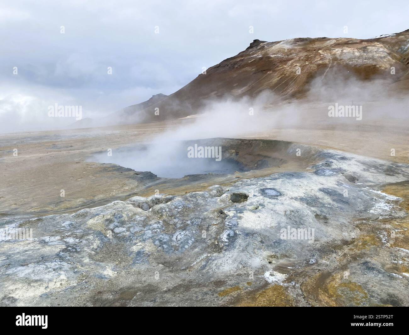 The image depicts a geothermal landscape with a large, steaming feature ...