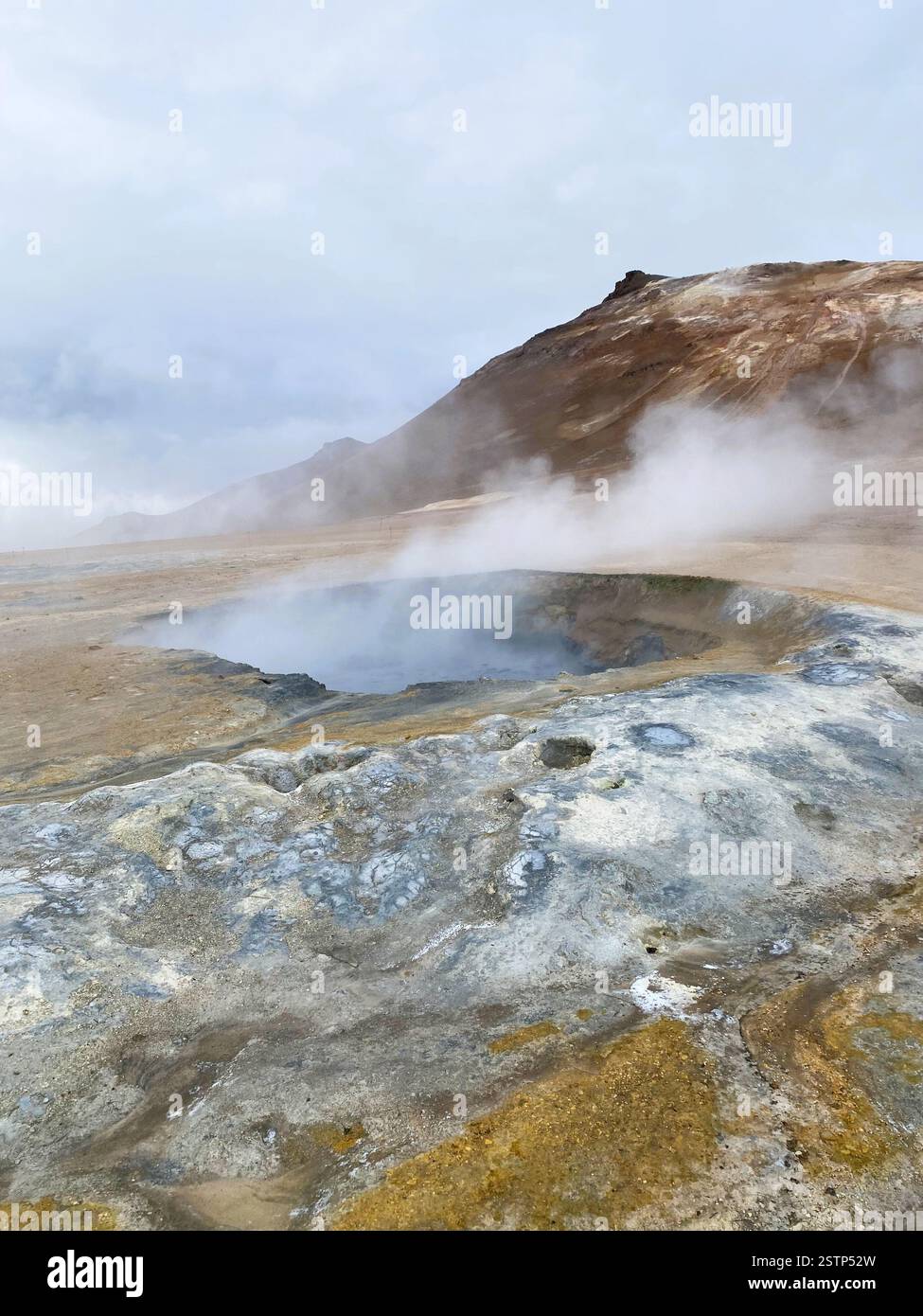 The image depicts a barren geothermal landscape with a circular hot ...