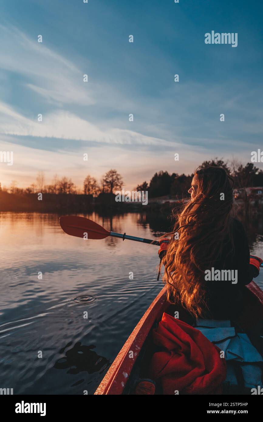 Back view of happy cute girl holding paddle in a kayak on the river ...