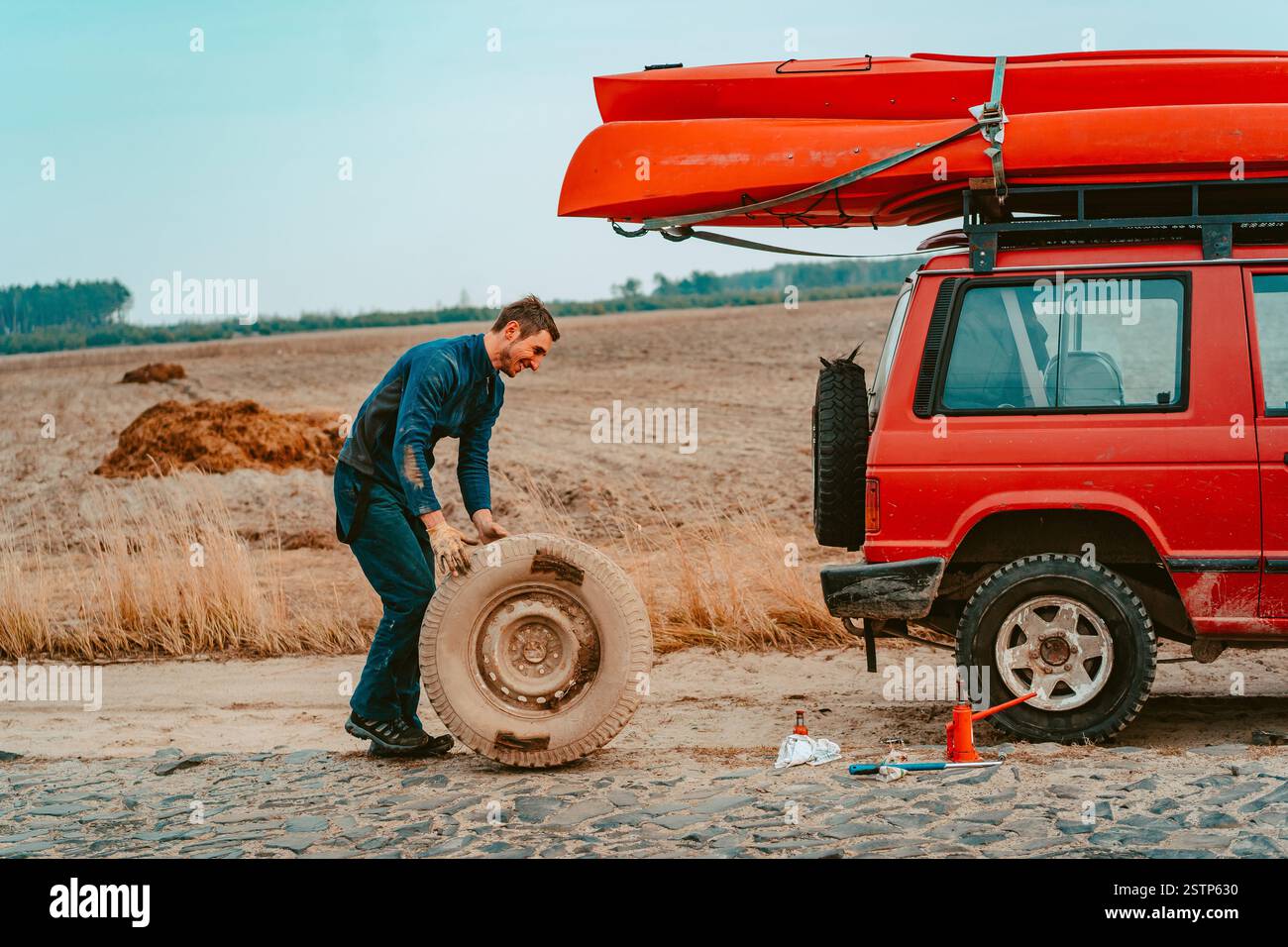 Man rolls a new replacement wheel to 4x4 off road truck Stock Photo - Alamy
