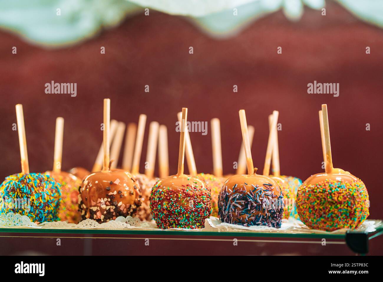 Apples in caramel and sprinkles. Street food Stock Photo - Alamy