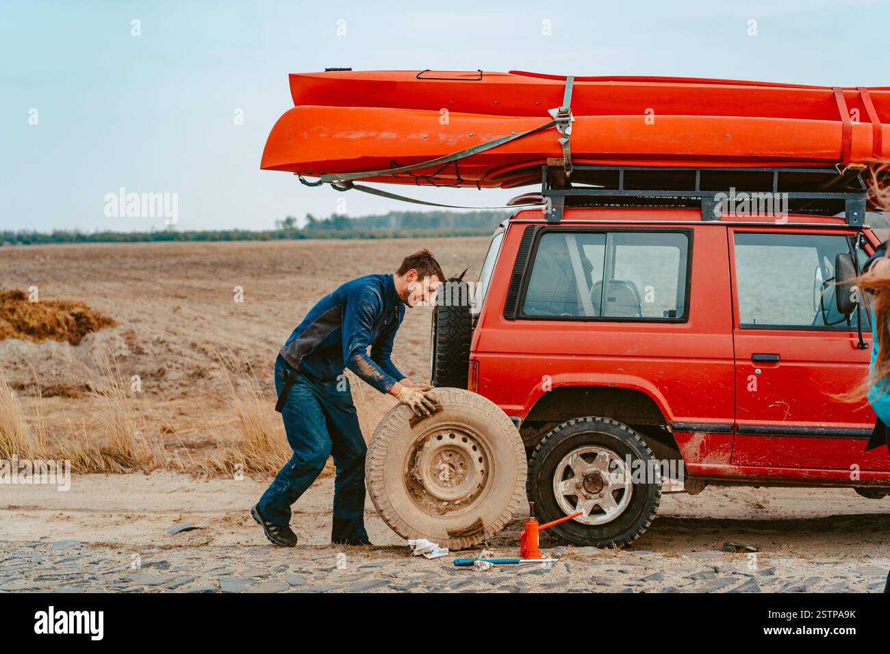 Man rolls a new replacement wheel to 4x4 off road truck Stock Photo - Alamy