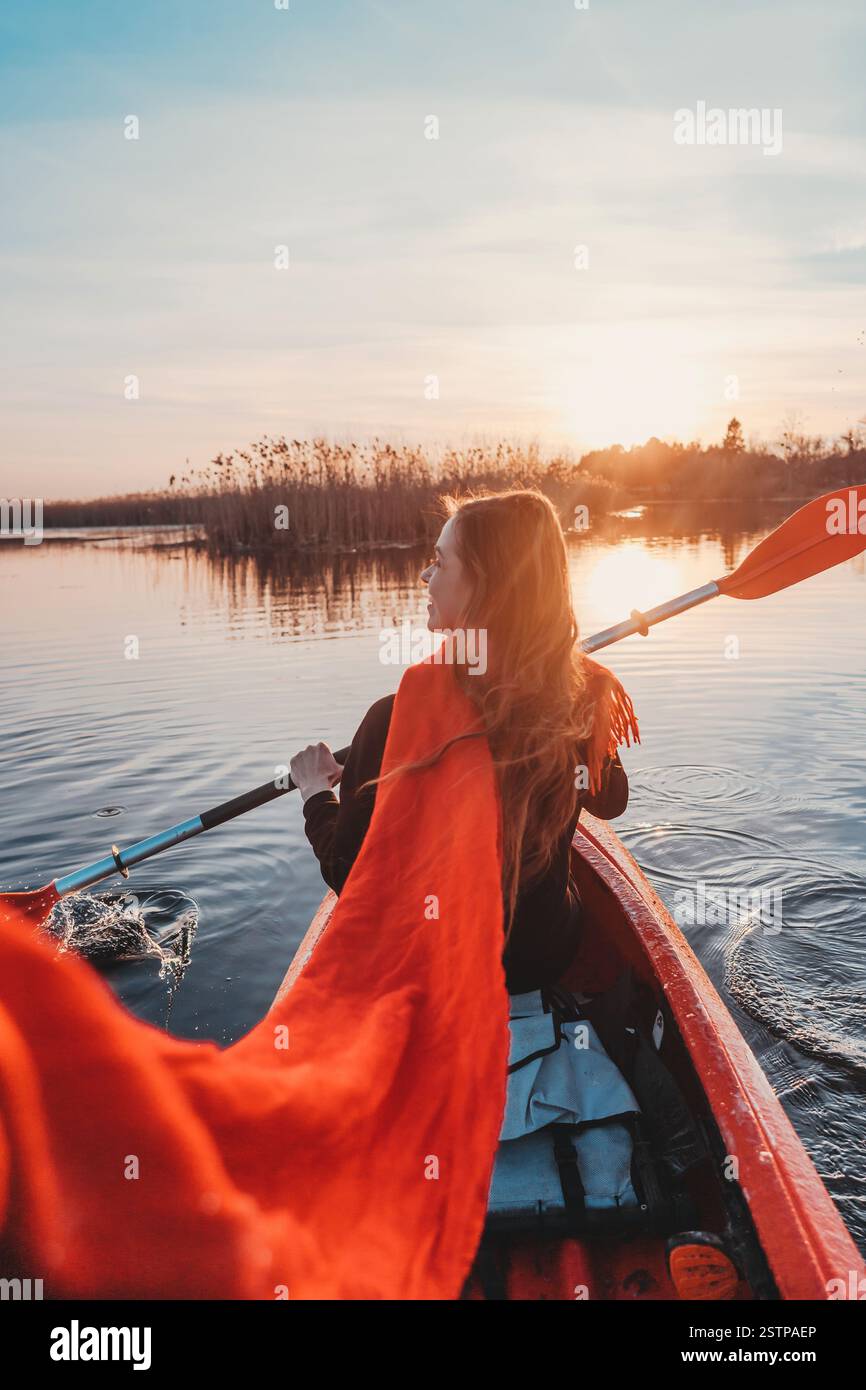 Back view of happy cute girl holding paddle in a kayak on the river ...