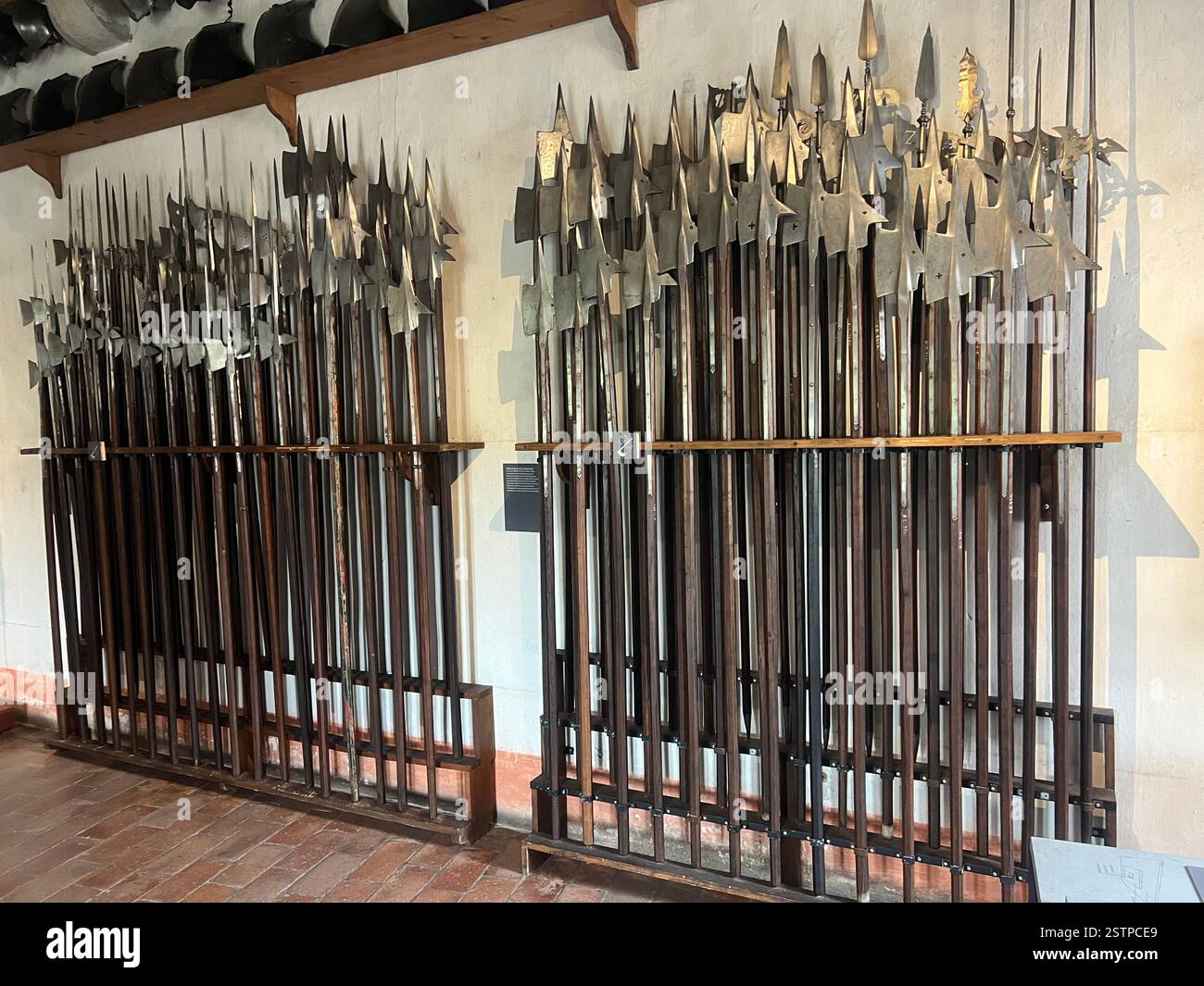 A row of medieval halberds displayed on a wooden rack in a historic ...