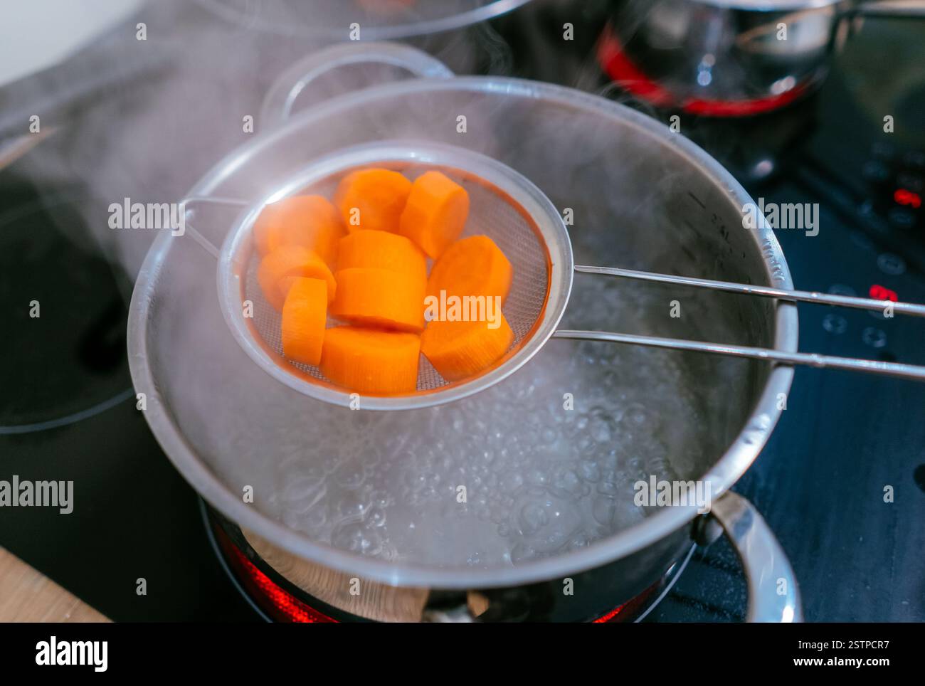 The image of a small amount of chopped carrots over a boiling pan ...