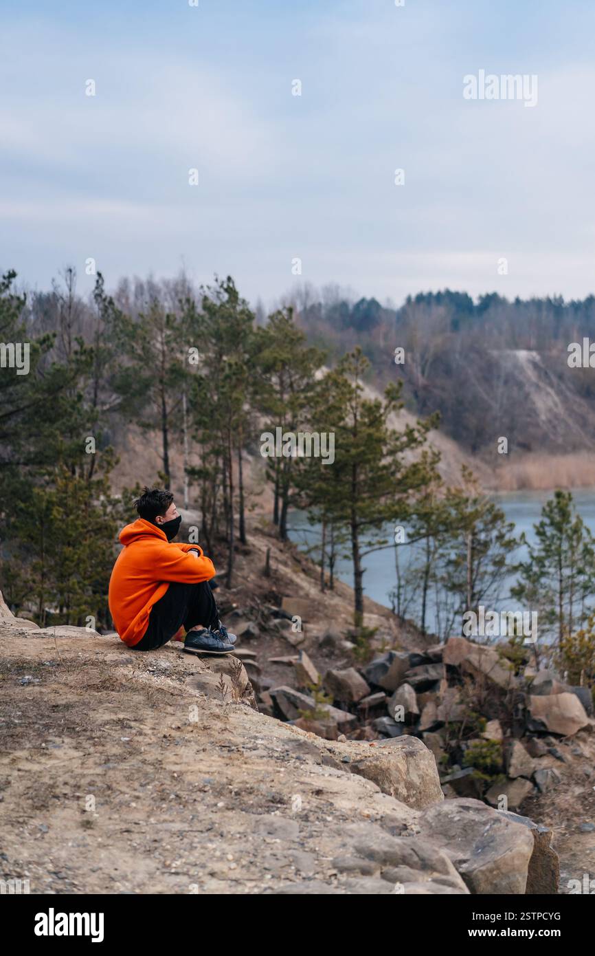 A young man sitting on the edge of a cliff poses for the camera Stock ...